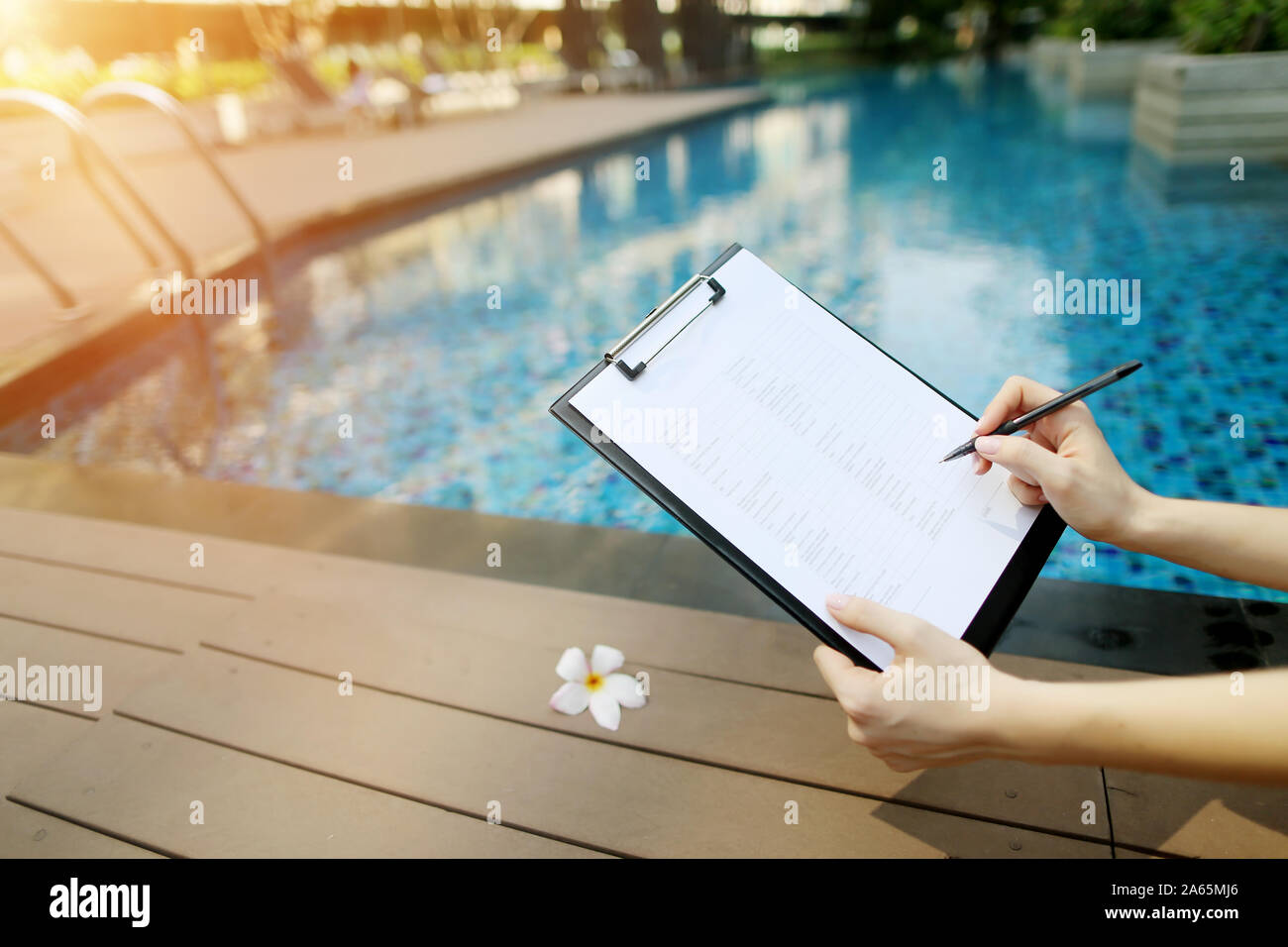 Focus on document, girl fills empty paper on background of pool. Front ...