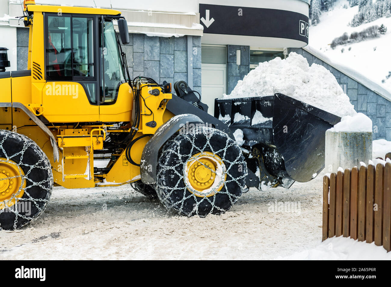 Big loader machine with steel metal chains removing big snow pile from ...