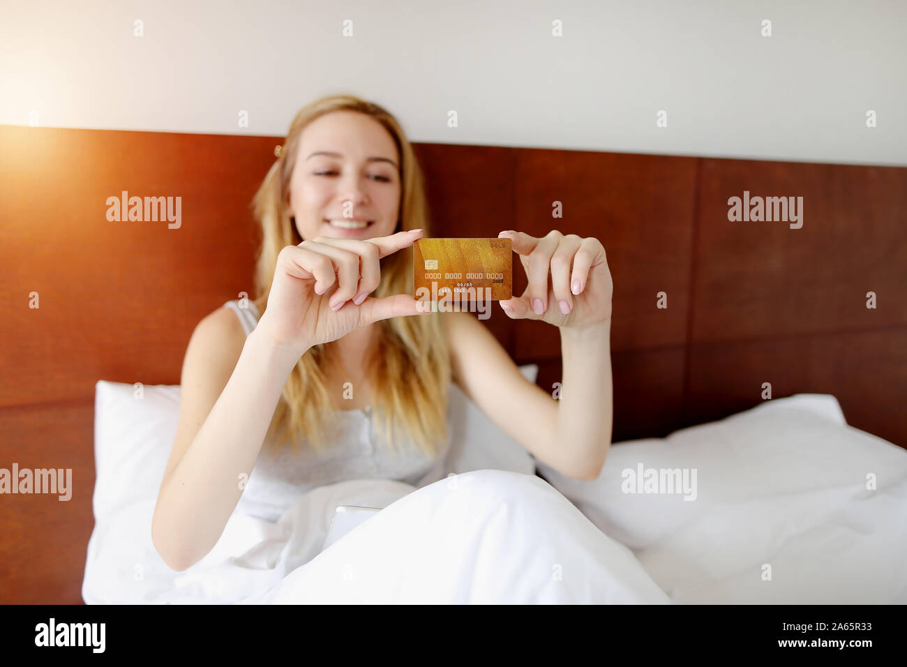 focus on debit card hold by young american woman in white bed with ...
