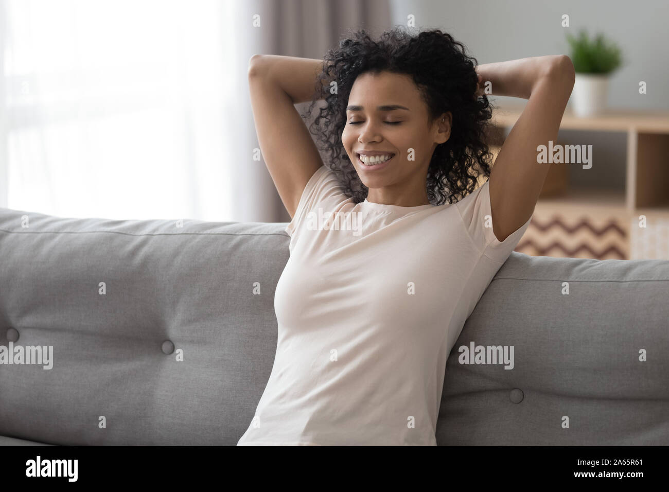 Smiling black woman relax on couch at home Stock Photo - Alamy