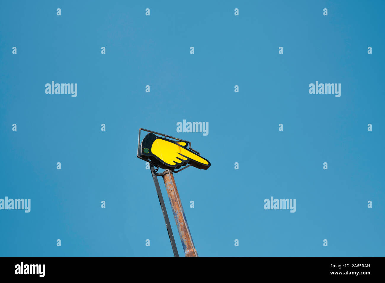 Quirky yellow finger pointing hand sign with a deep blue sky background ...