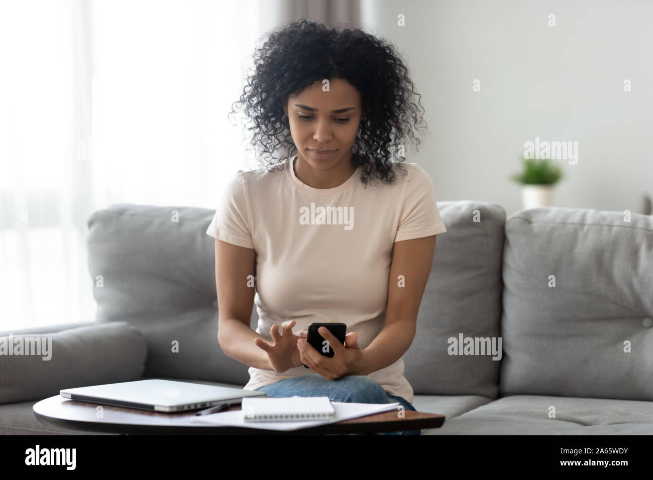 African American woman busy using smartphone at home Stock Photo - Alamy