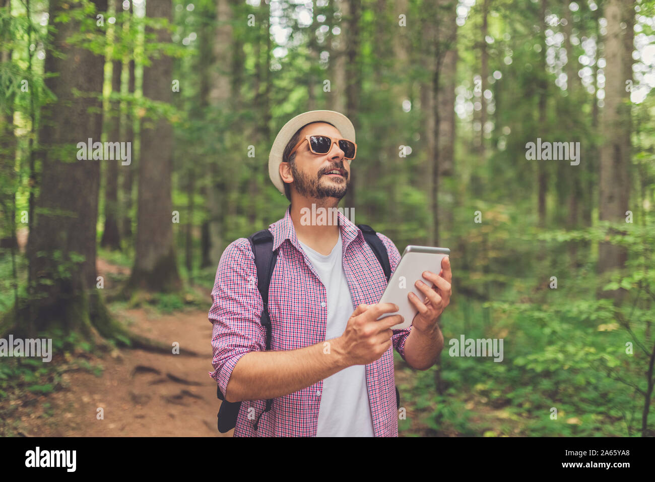 Modern hipster guy holding tablet device in nature. Travel, technology ...