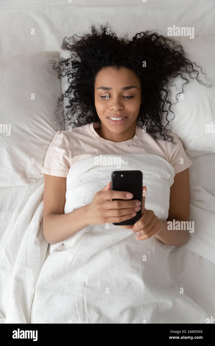 Black girl using cellphone waking up in bed in morning Stock Photo - Alamy