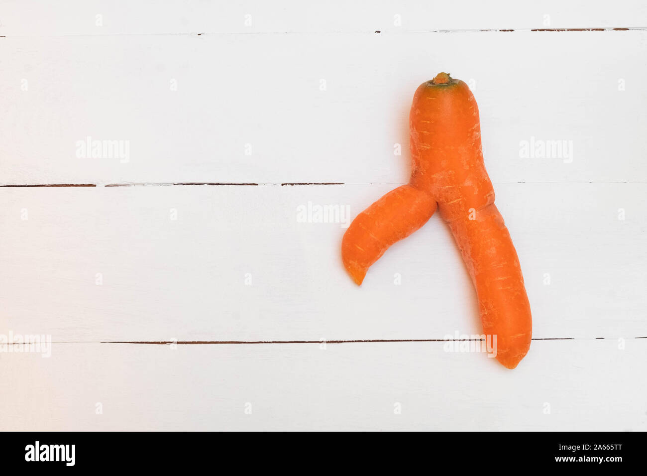Food waste concept. Ugly deformed carrot on white wooden background ...