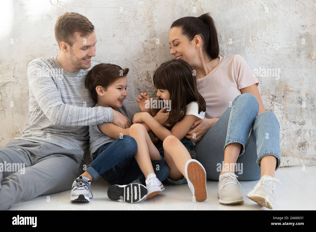 Happy young parents with little kids sitting on floor Stock Photo - Alamy