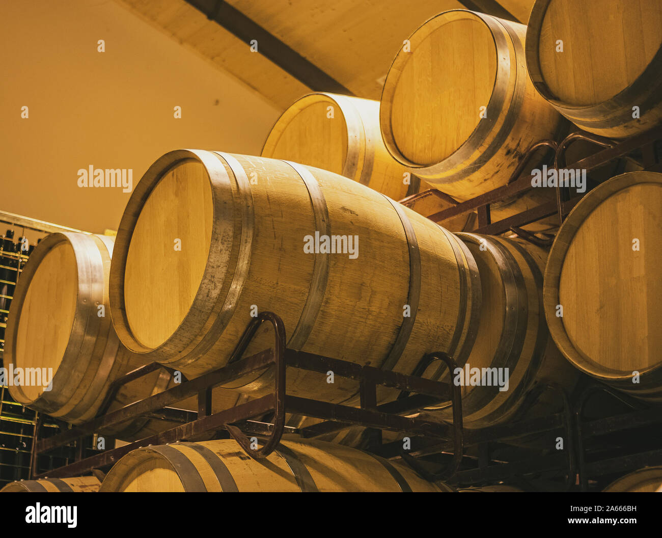 Set of wine barrels stacked in a metal structure inside a dark wine ...