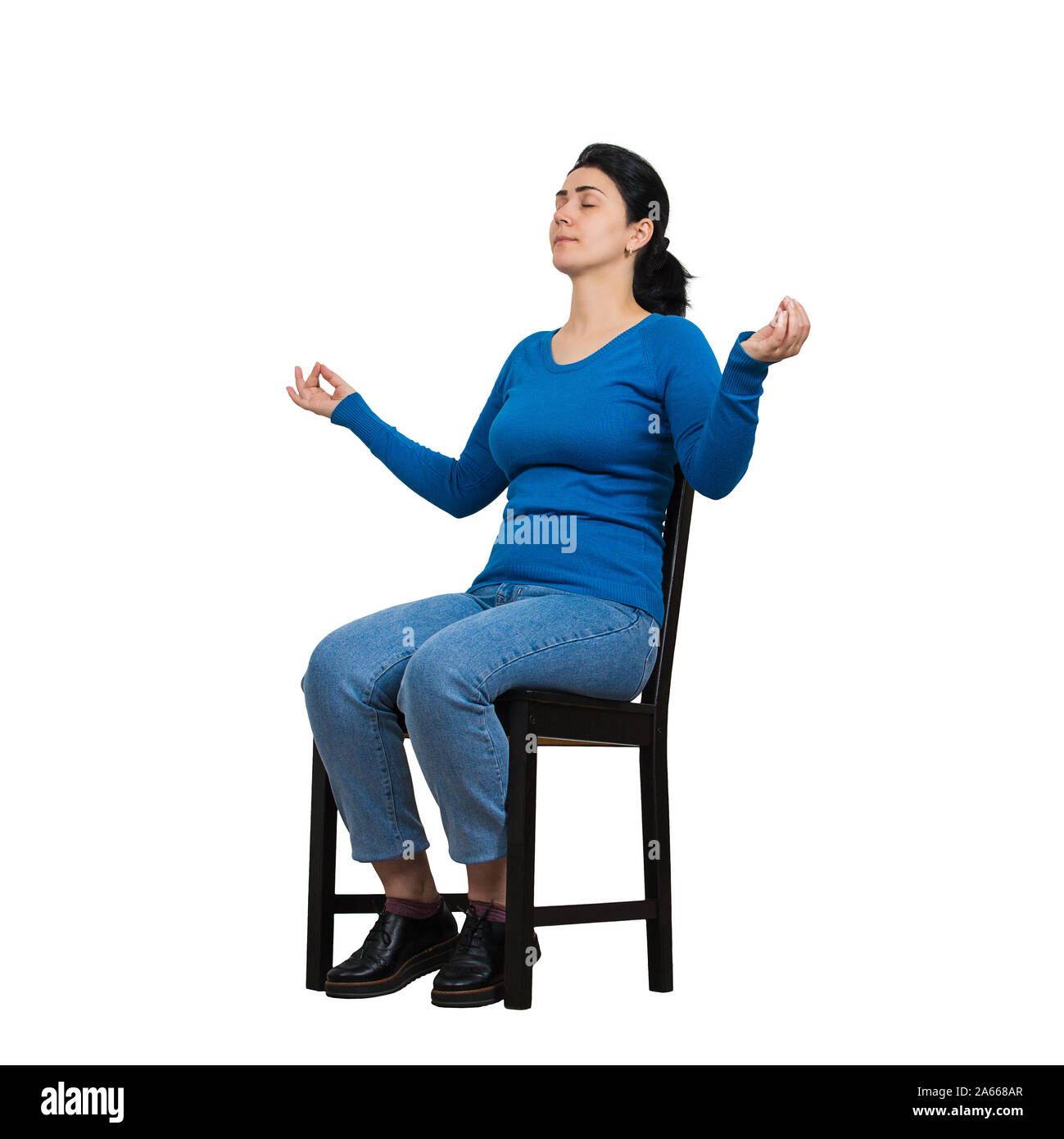 Casual young woman sitting on a chair, eyes closed, hands showing zen ...