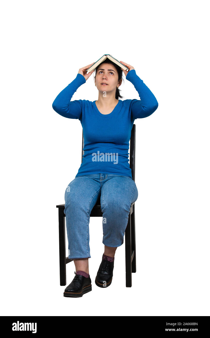 Confused woman student, seated on a chair, keeps open book over head ...