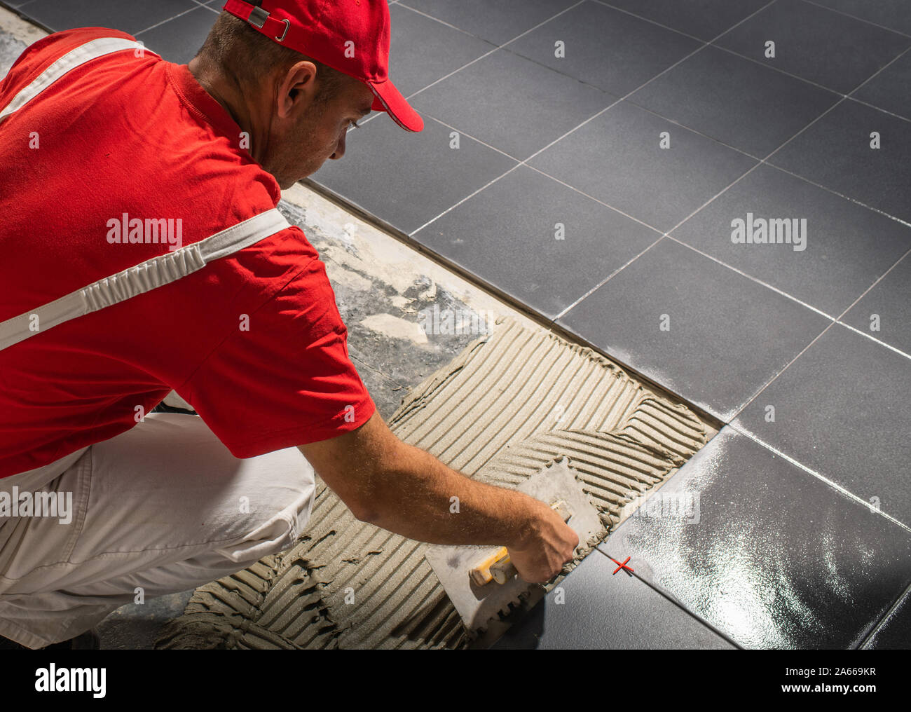 A construction worker putting on new floor tiles Stock Photo - Alamy