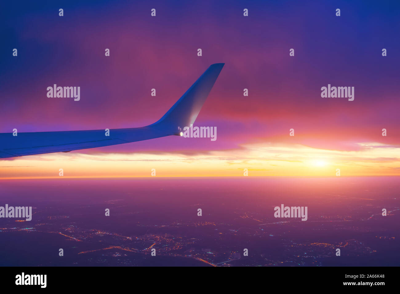 Sunset sky from an airplane side wing view of the horizon and city ...