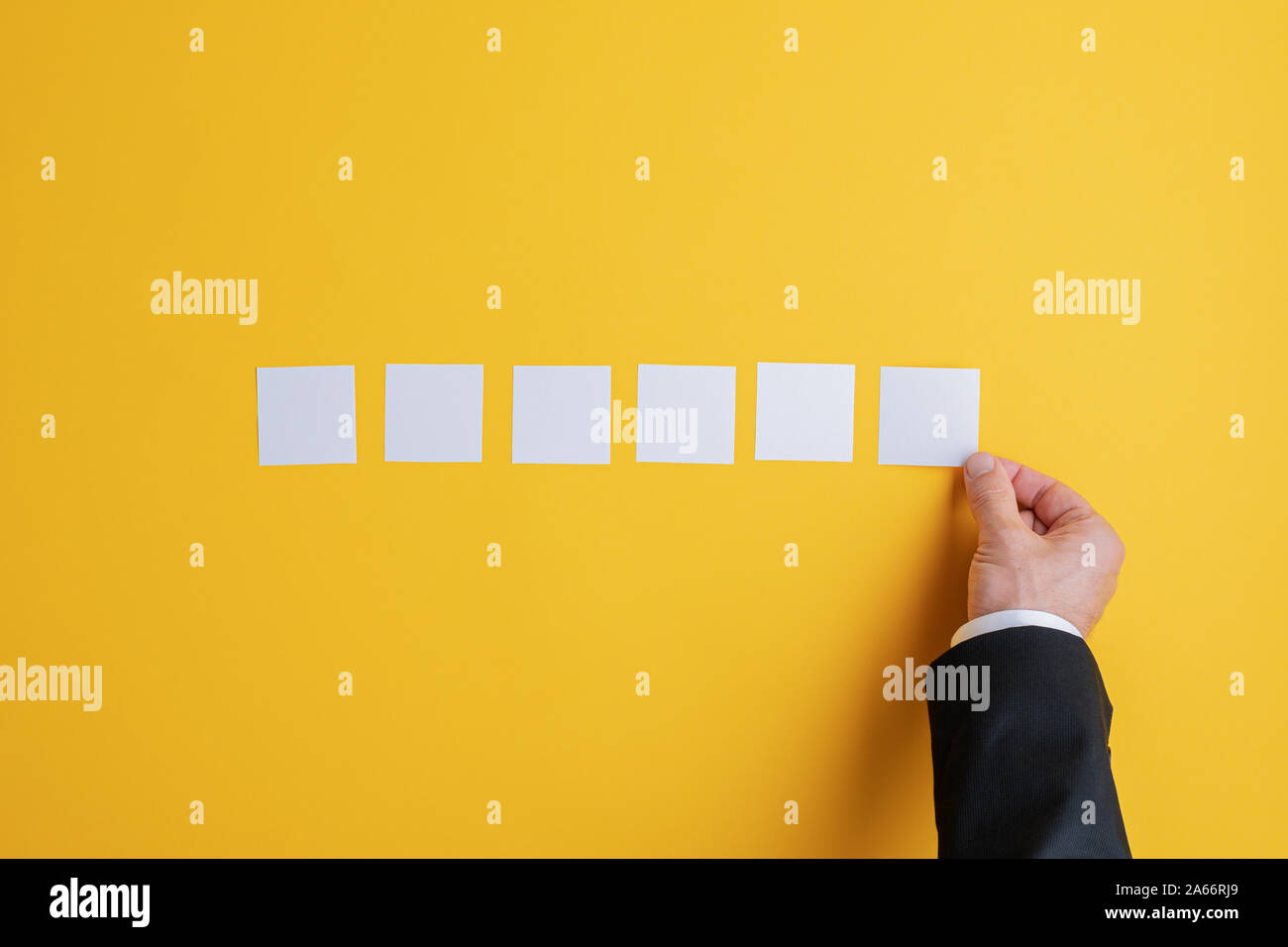 Hand of a businessman placing six blank post it papers in a row. Over ...