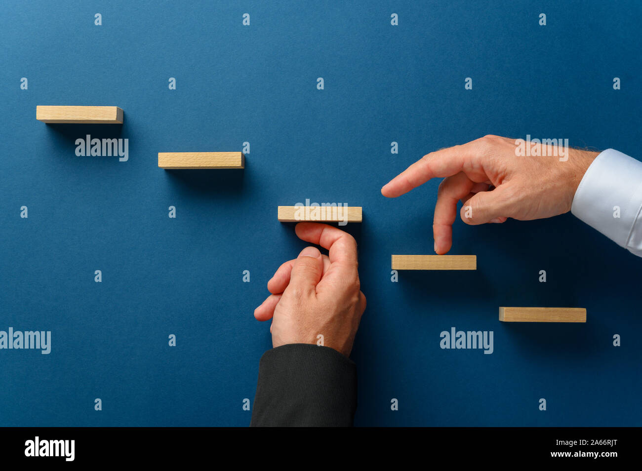 Hand of a businessman supporting wooden steps for his partner to walk ...