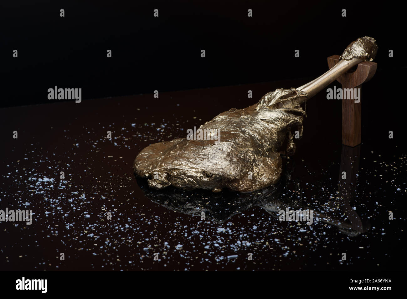 roasted meat with bone in gold leaf on a dark background Stock Photo ...