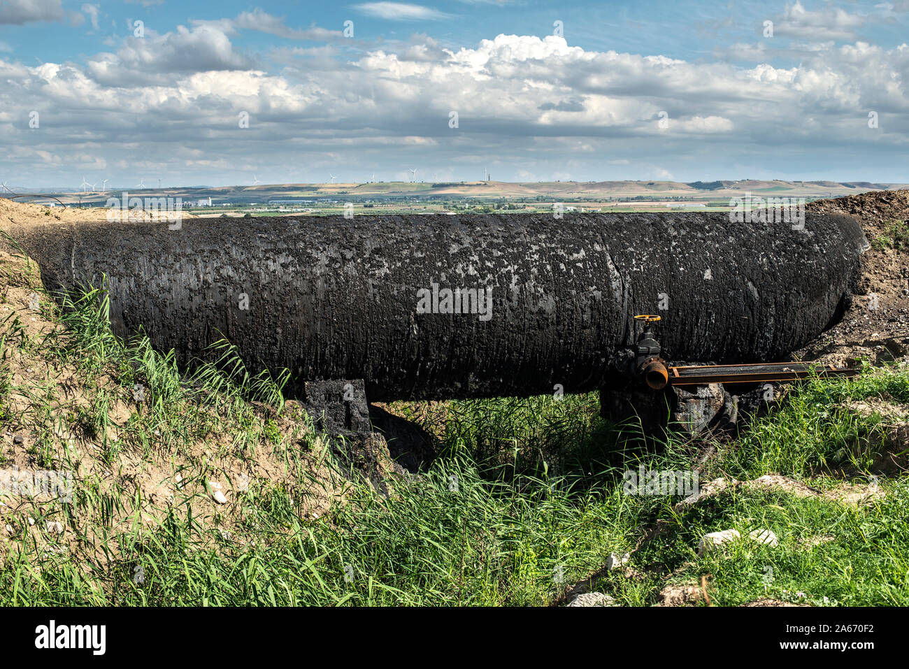 Black Oil pipeline goes out above the ground. Oil-stained pipe. Concept ...