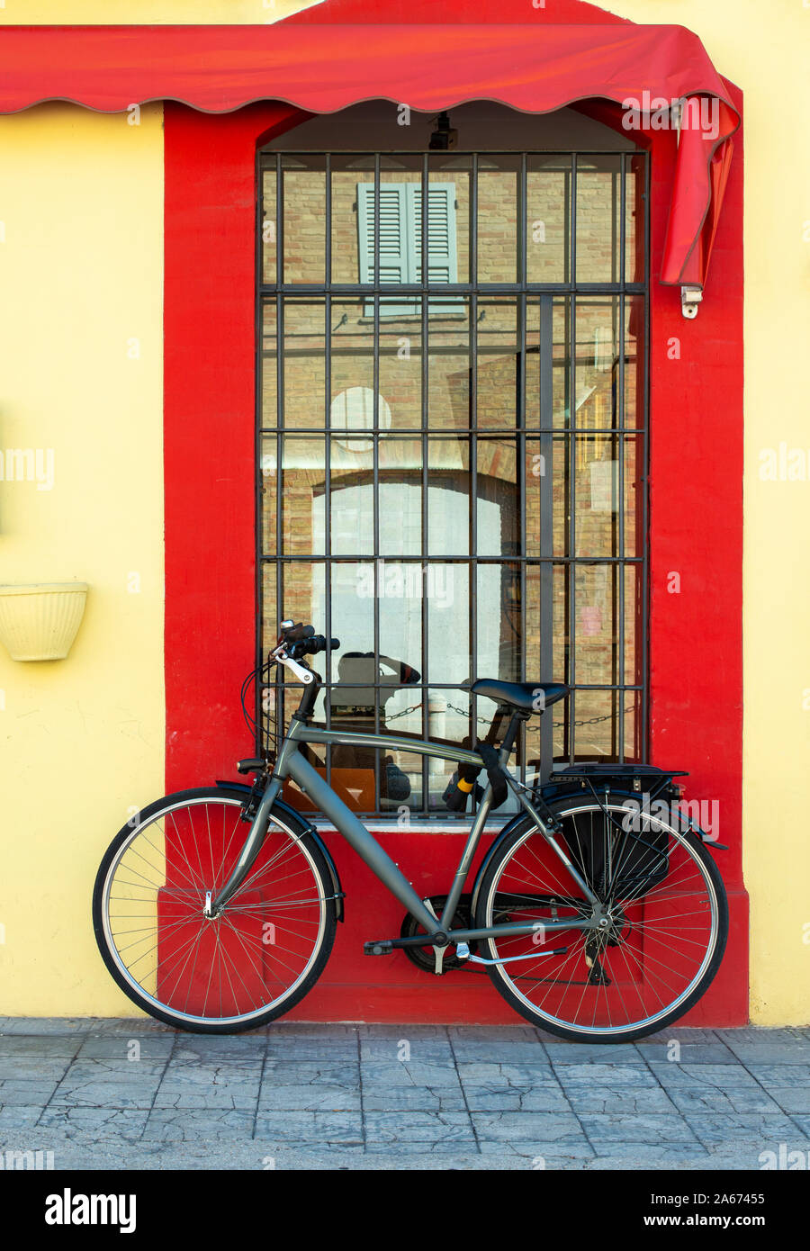 Grey bike in front of yellow facade and red window. Bicycle with trunk ...