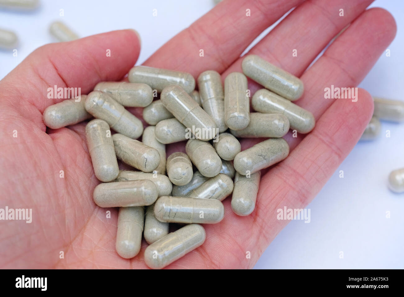Capsules with iron in a female hand. Hand with capsules of gray color ...