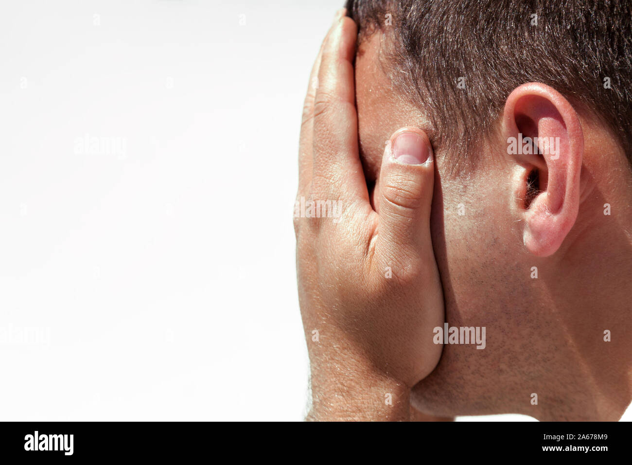 A praying young man. Man with face in his hands isolated on a white ...