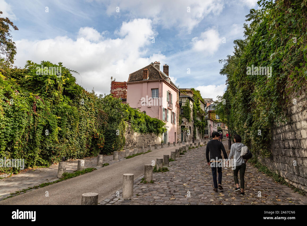 Couple walking up cobblestone streets of Montmartre district in Paris ...