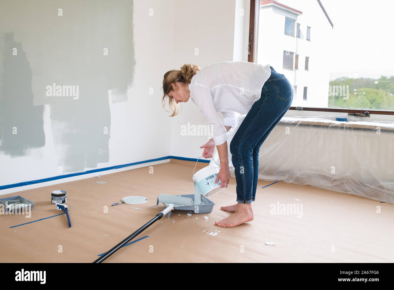 Woman pouring white paint in a bucket Stock Photo - Alamy