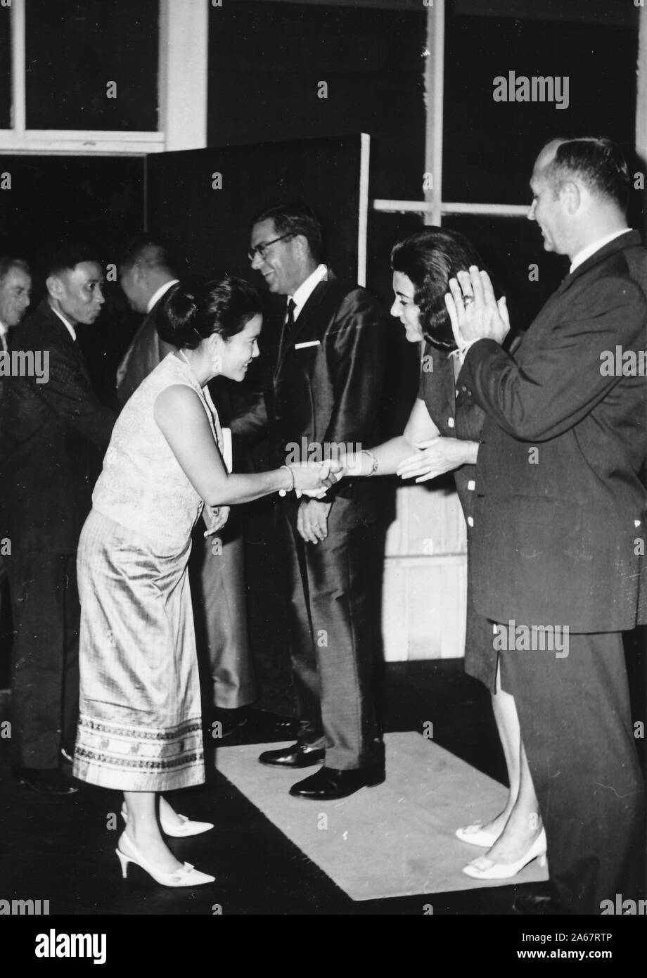 Full-length shot of formally dressed men and women greeting each in a ...
