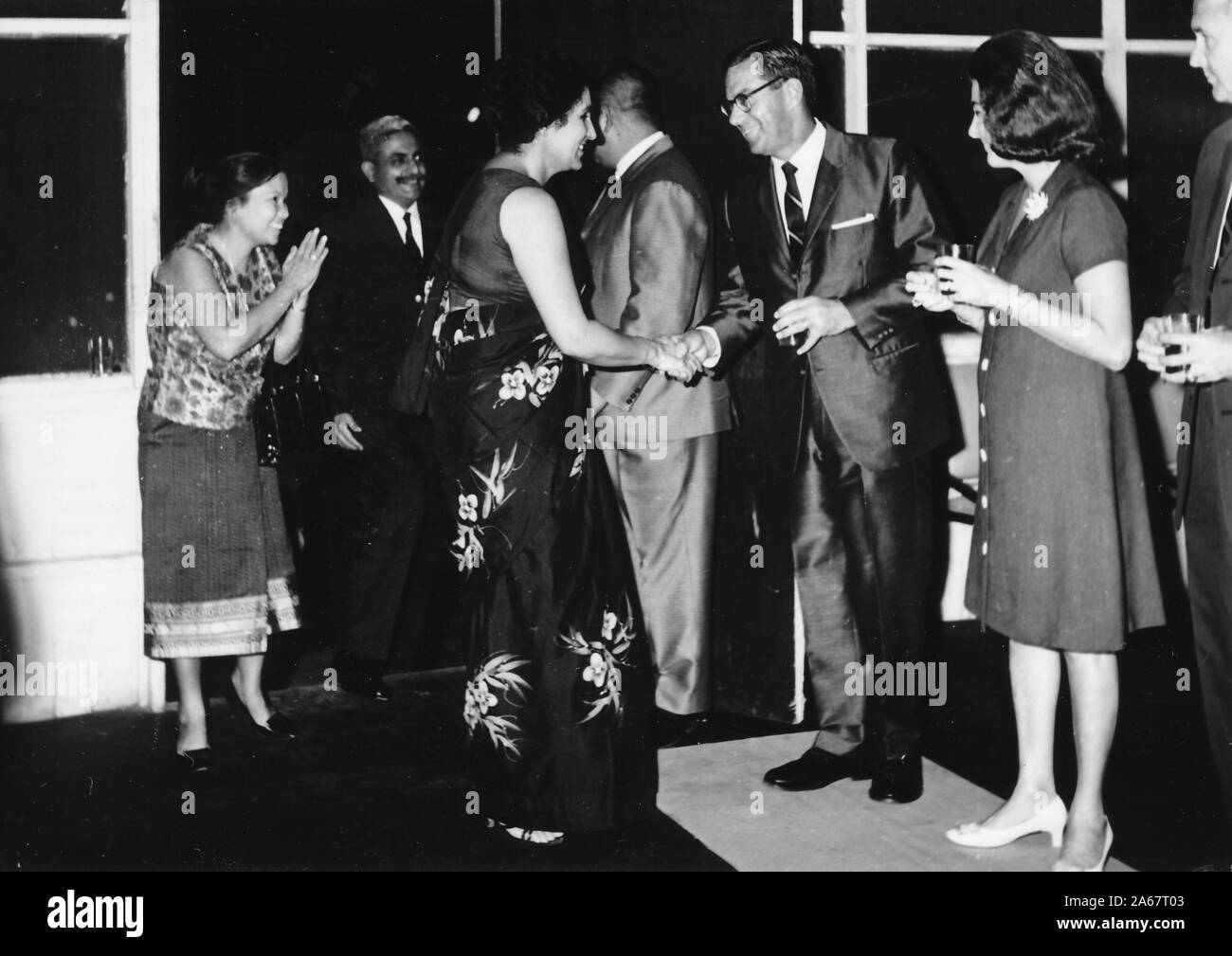 Full-length shot of formally dressed men and women greeting each in a ...