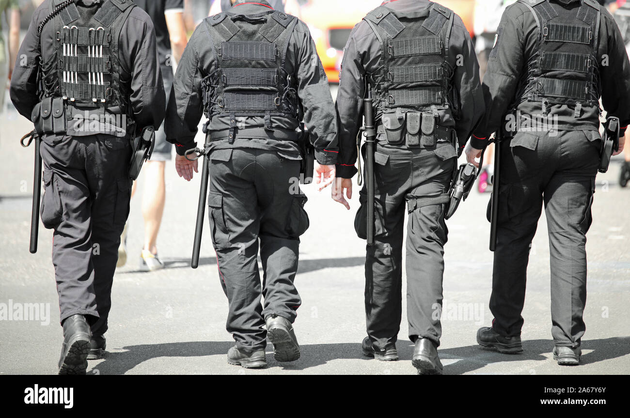 Four policemen with anti-riot uniform patrolling the city Stock Photo ...