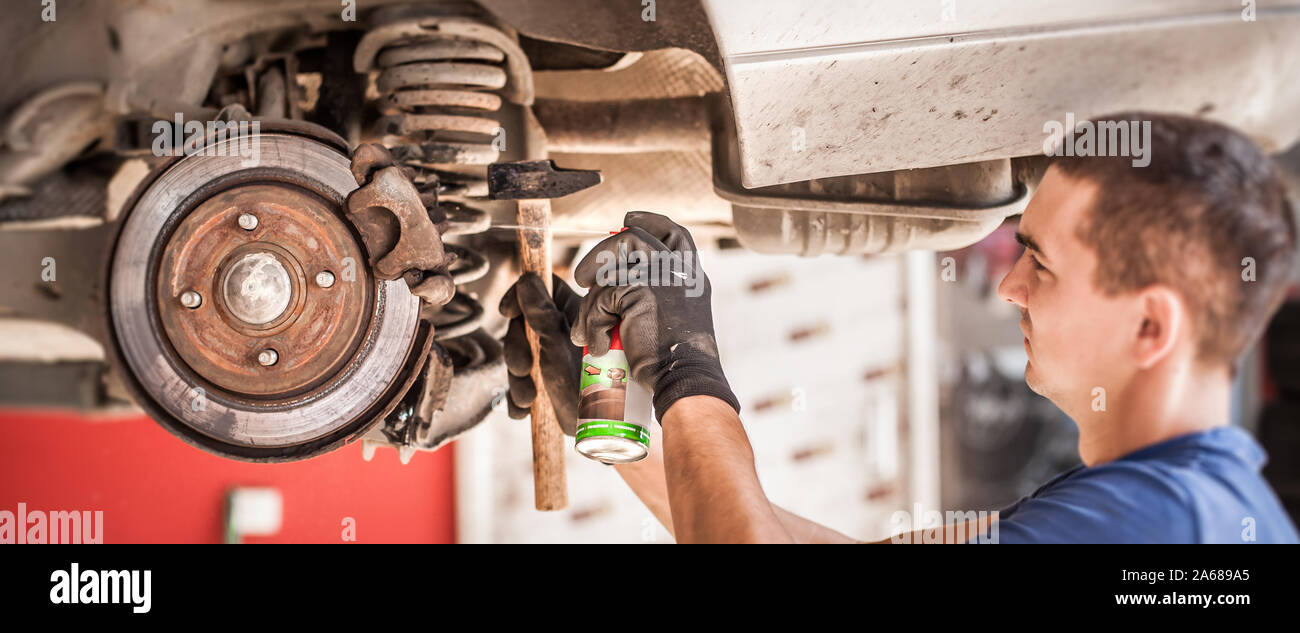 Car master mechanic repairer lubricates the screws with a machine parts ...