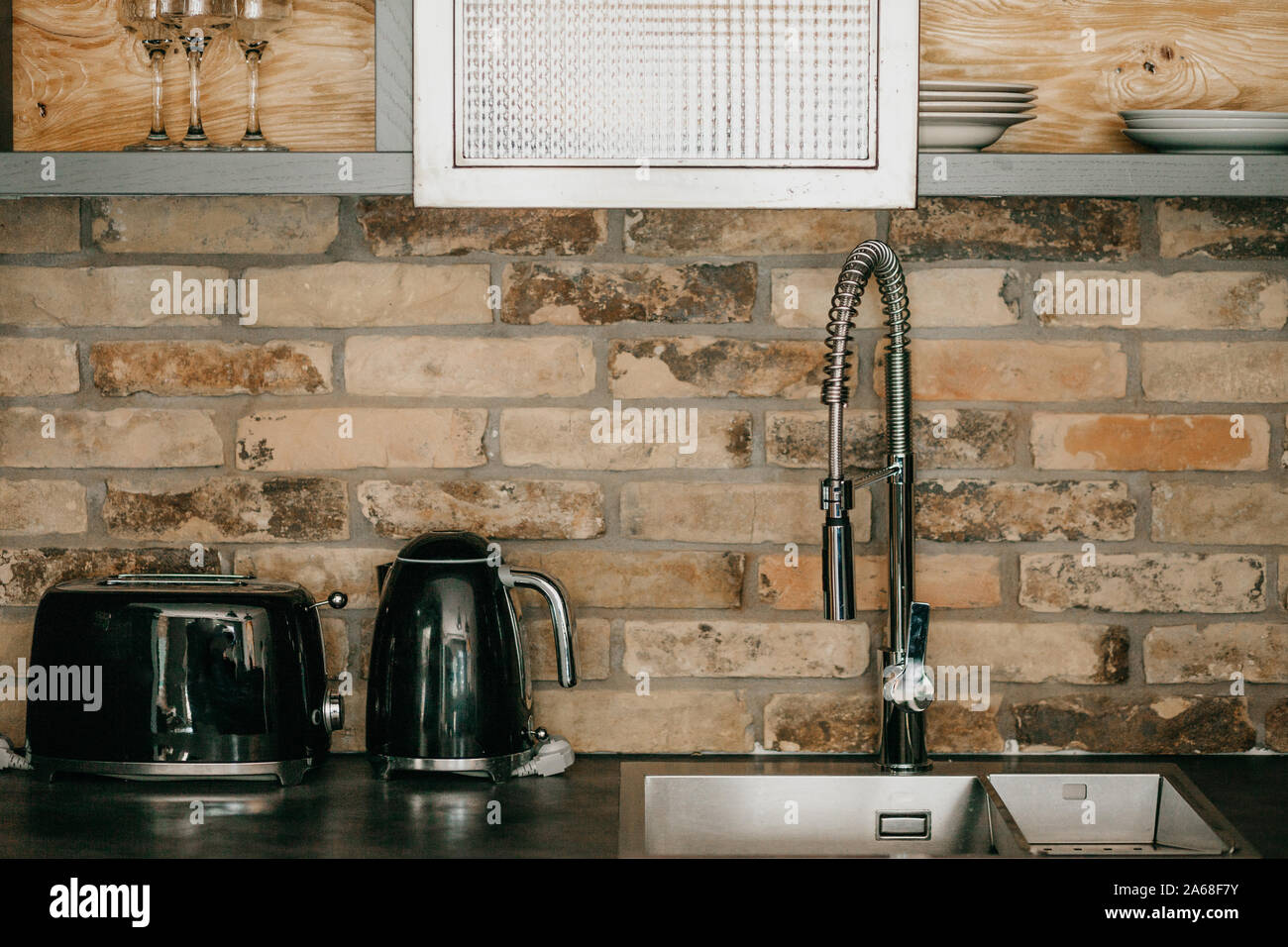 Kitchen with a brick wall with a faucet, kettle, toaster and shelves on ...