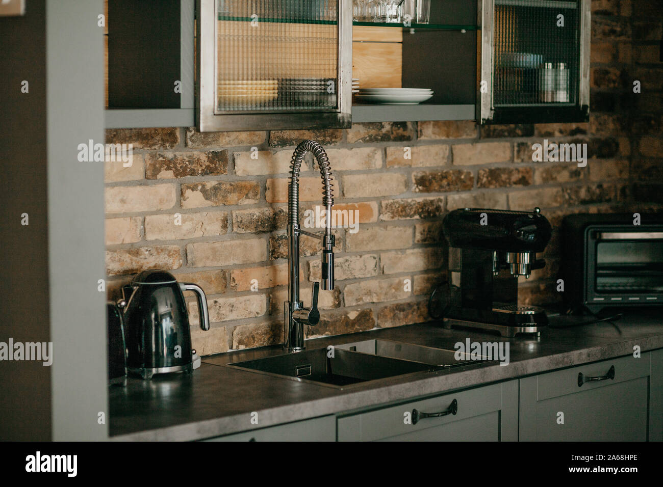 Kitchen with a brick wall with a faucet, kettle, coffee maker and ...