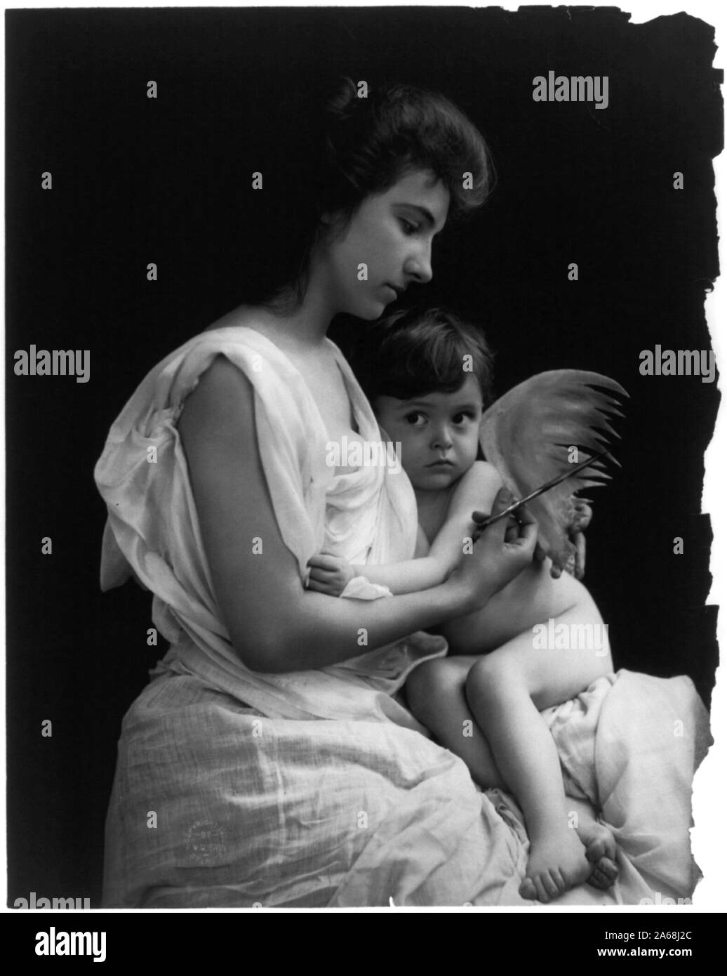 Woman holding scissors and winged child Stock Photo - Alamy