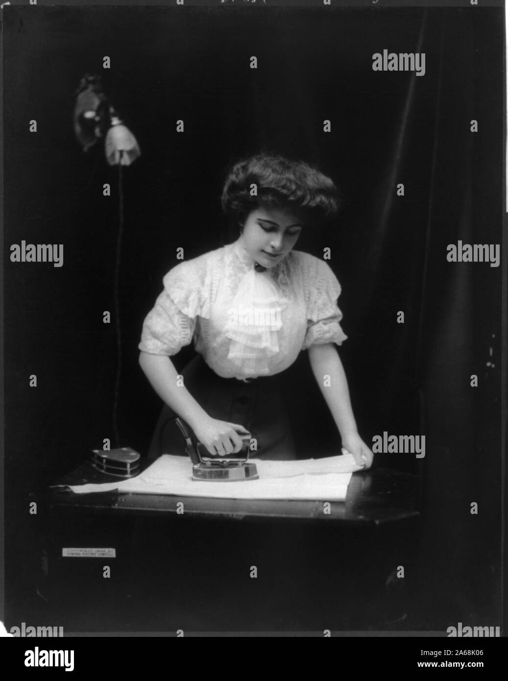 Woman using electric iron plugged into light socket Stock Photo - Alamy