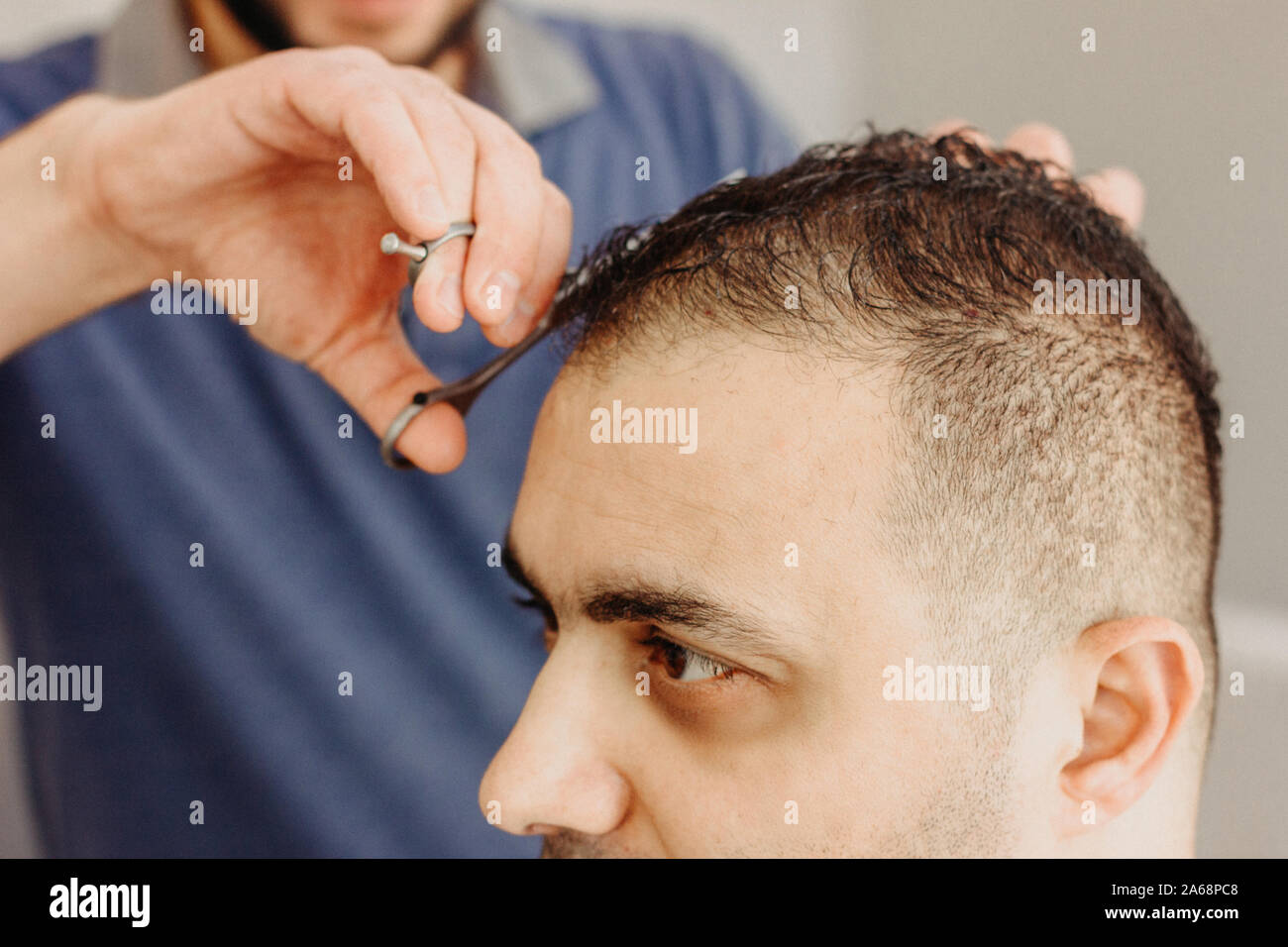 Barber making stylish haircut with professional scissers in barber shop ...