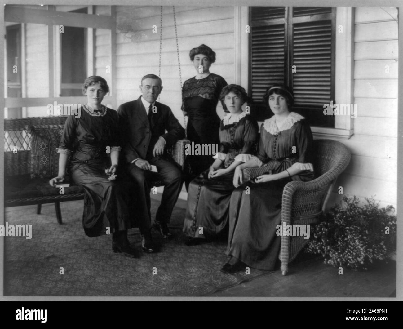 Woodrow Wilson, seated posed on swing on porch, facing front, with his ...