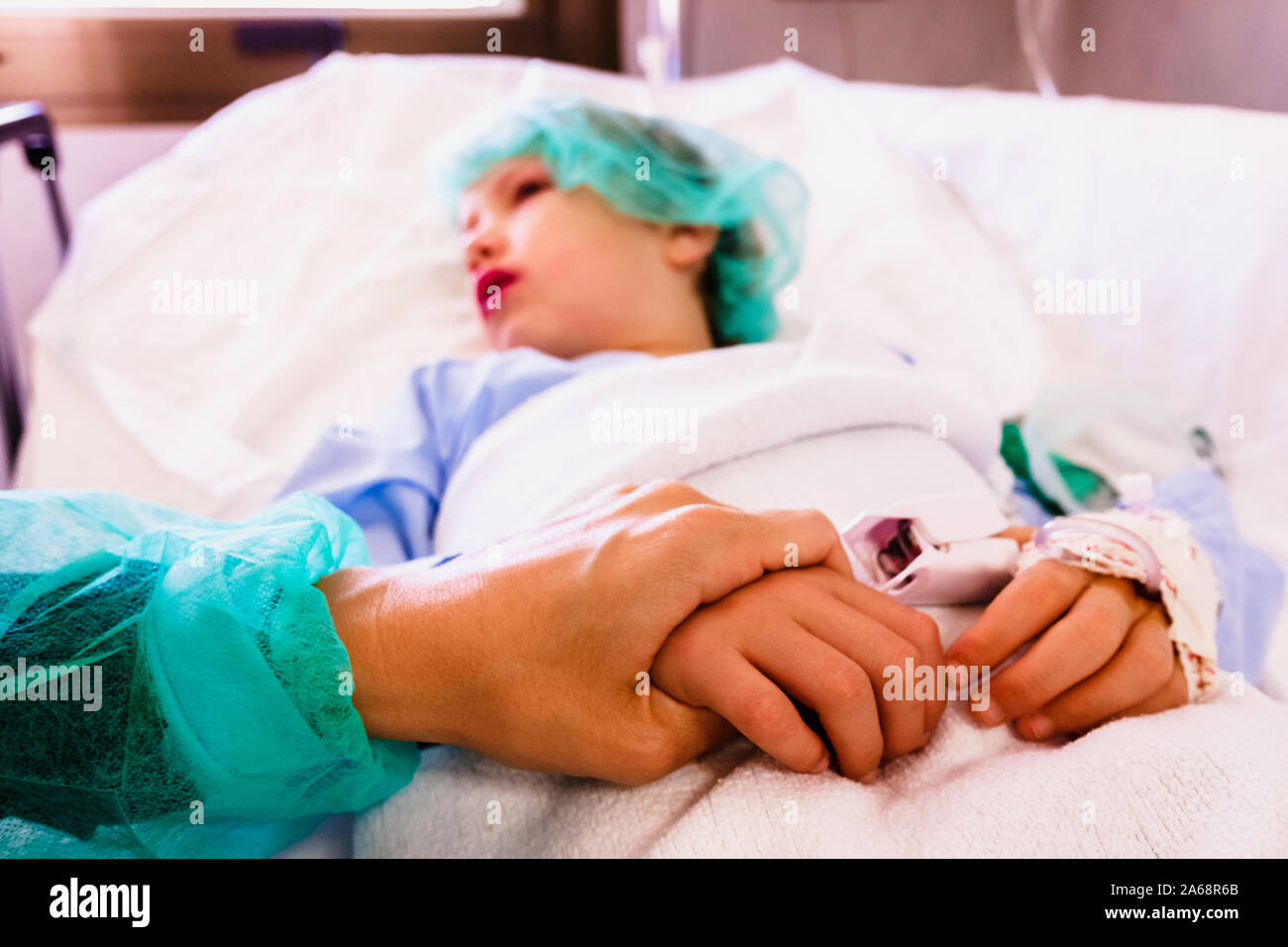 Mother holds her son's hand to encourage her in a hospital bed before ...
