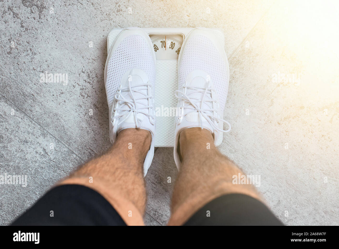 Weighing. Men feet standing on weigh scales Stock Photo - Alamy