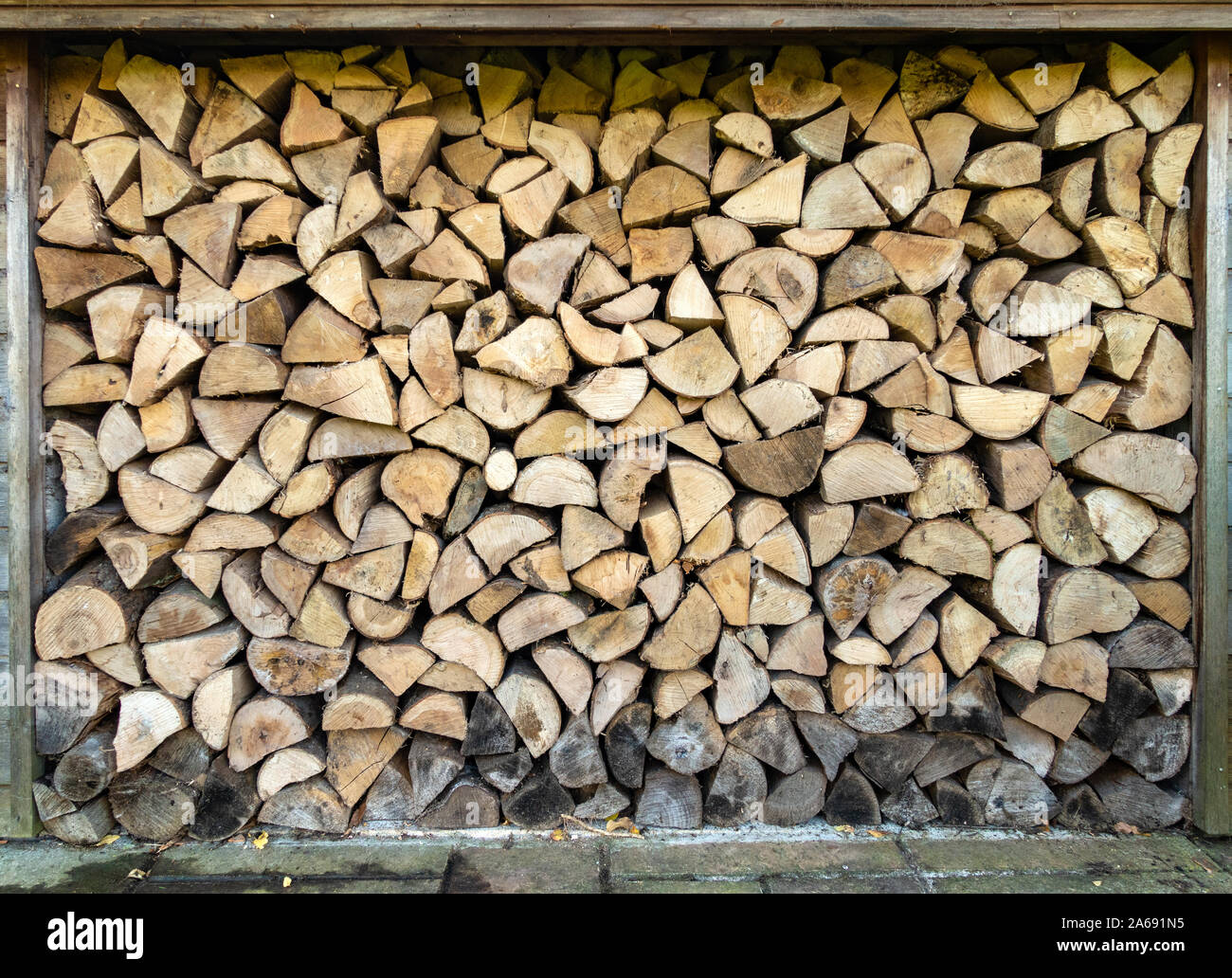 Wood logs piled high in a log store Stock Photo - Alamy