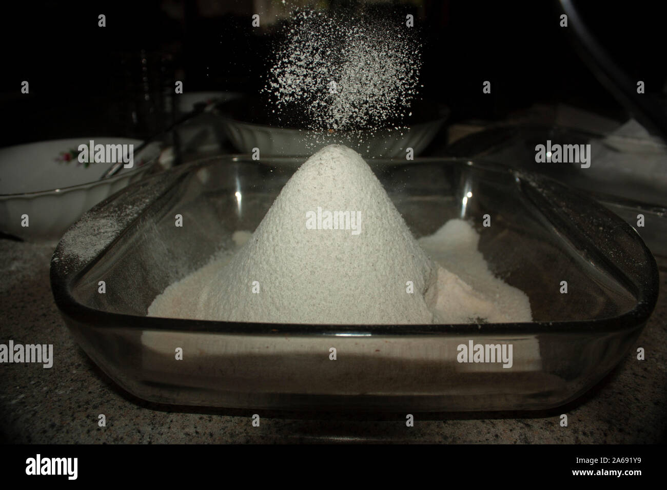 Almond flour sifted particles slowly falling forming volcano with sugar ...