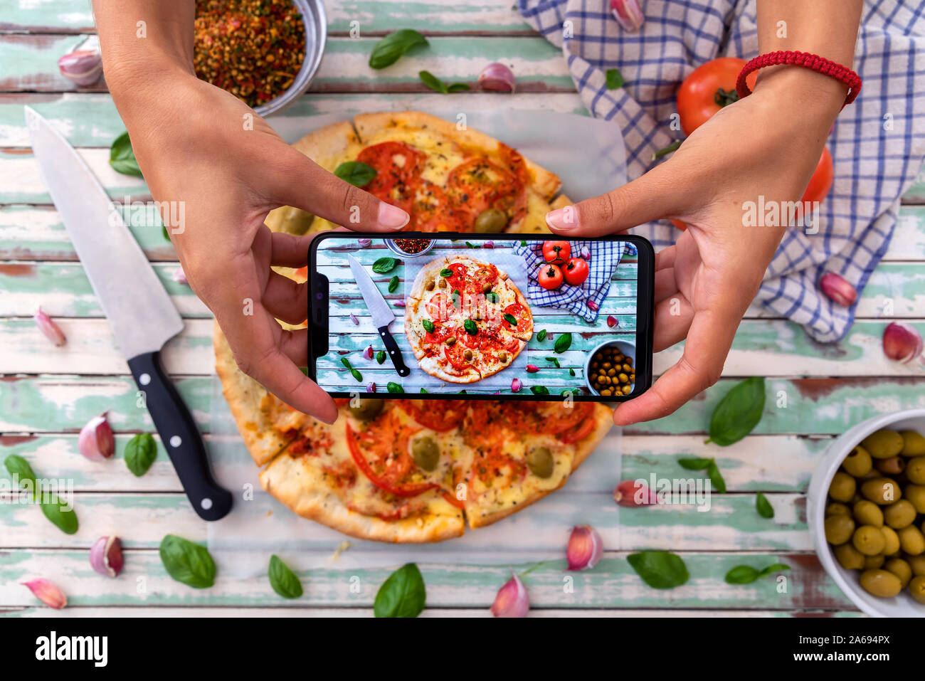 Woman taking pictures of a made wood fired pizza viewed from above on ...