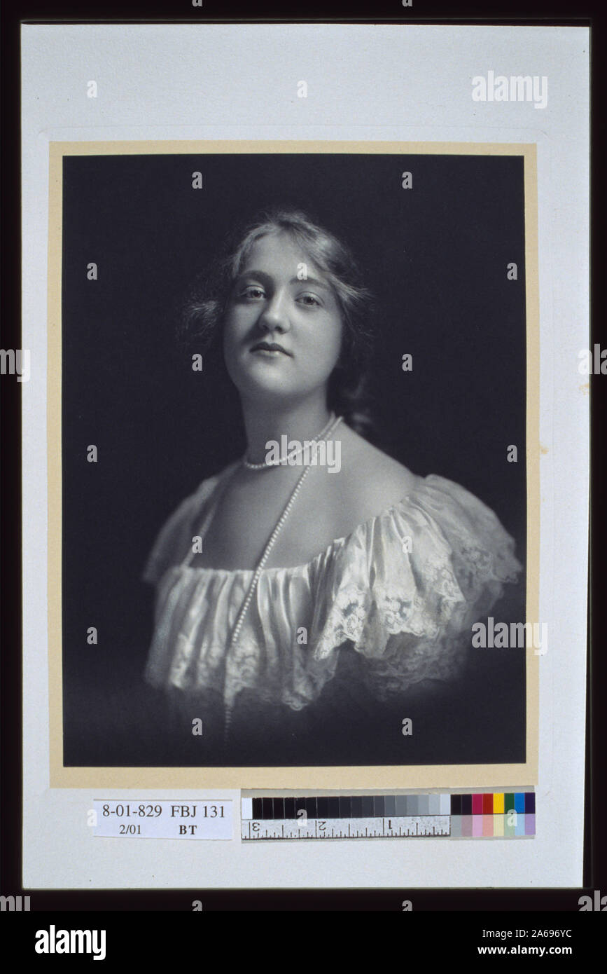 Young woman wearing an off-the-shoulder dress and long pearl necklace ...