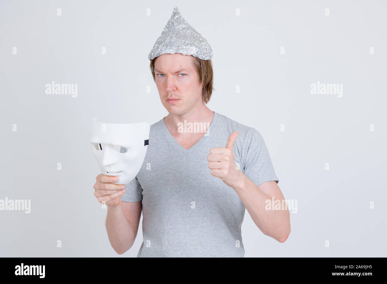 Young man with tinfoil hat holding white mask and giving thumbs up ...