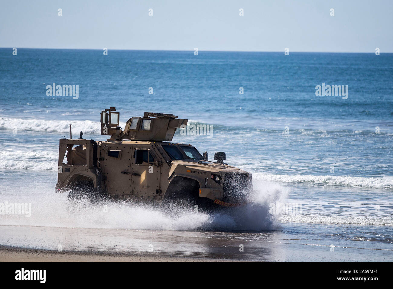 U.S. Marines drive a Joint Light Tactical Vehicles through the water at ...