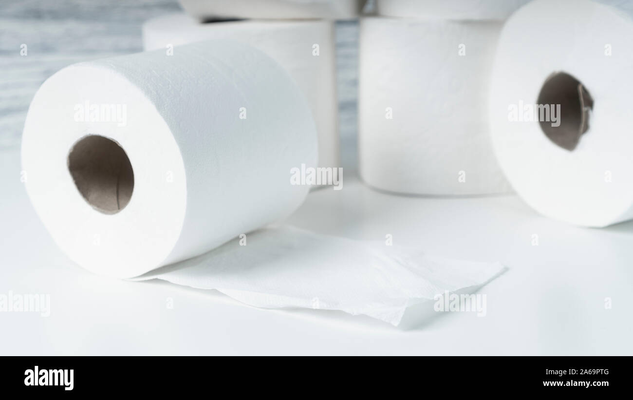 A pile of toilet paper rolls on a white table on a background of blue ...