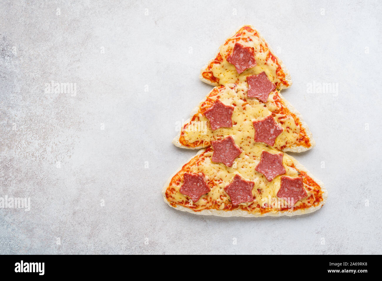 Pizza shaped as Christmas tree decorated with stars made of pepperoni ...