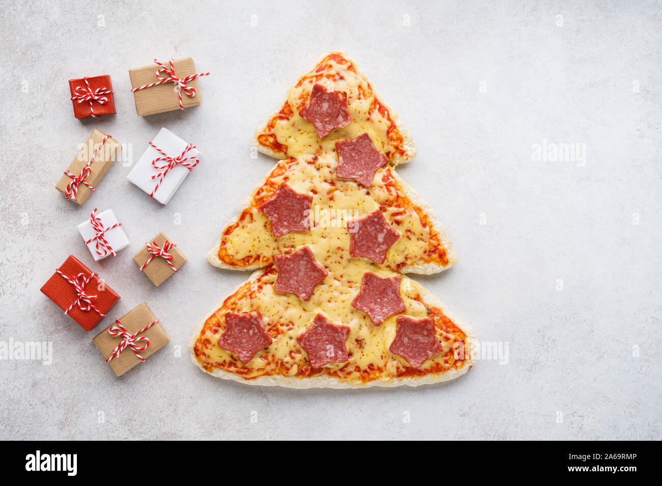 Christmas pepperoni pizza shaped as Xmas tree and gift boxes on light ...