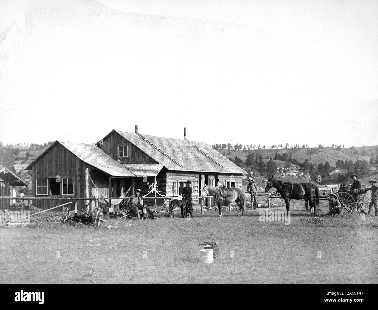 Farm equipment, horses, wagons, dogs, cowboys and others posed in front ...