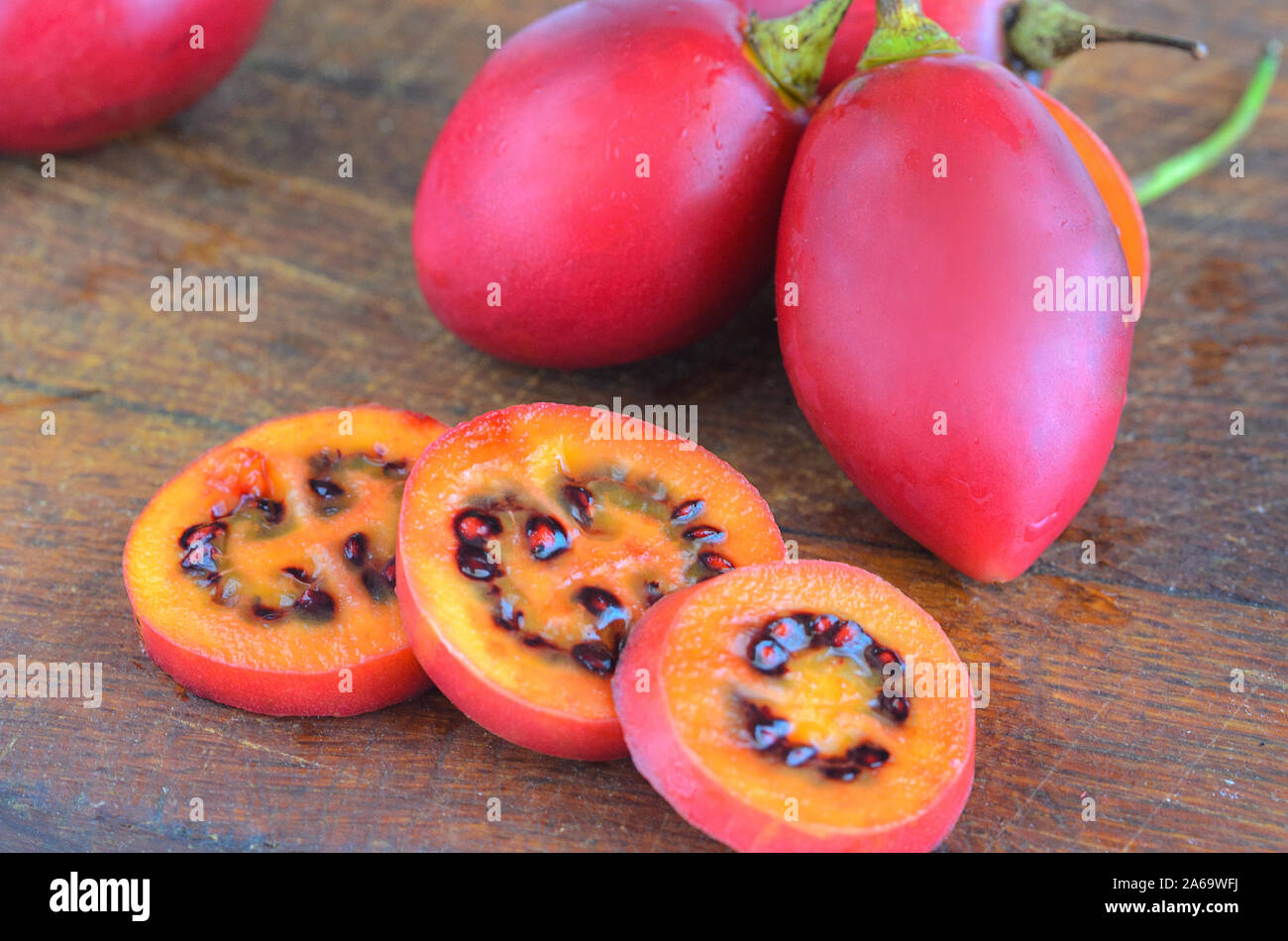 Red tamarillo or tree tomato cut into slices on cut board. Exotic fruit ...