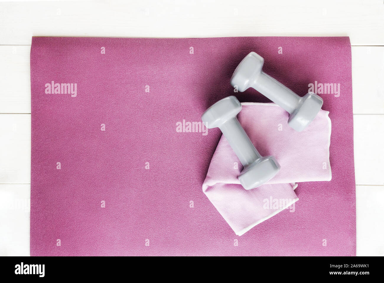 Open exercise mat, two dumbbells and sport towel on background with ...