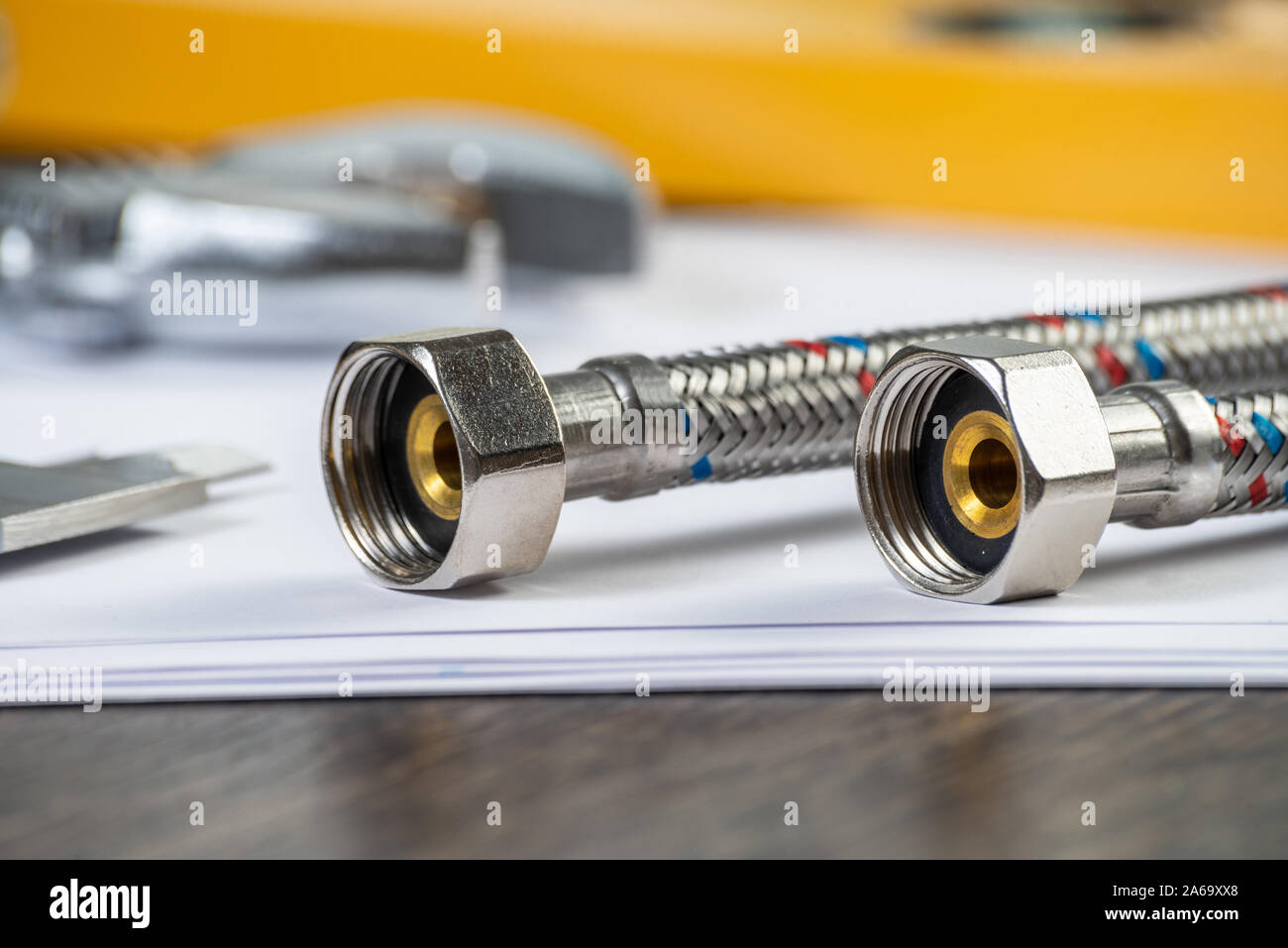 Water braided metal hose and hosepipe fittings laying on table. Close ...