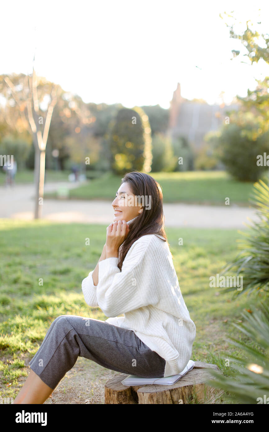 Chinese nice girl sitting on stump in park Stock Photo - Alamy